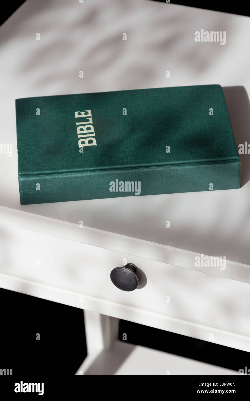holy bible in the morning light on a night table with shadowing through ...