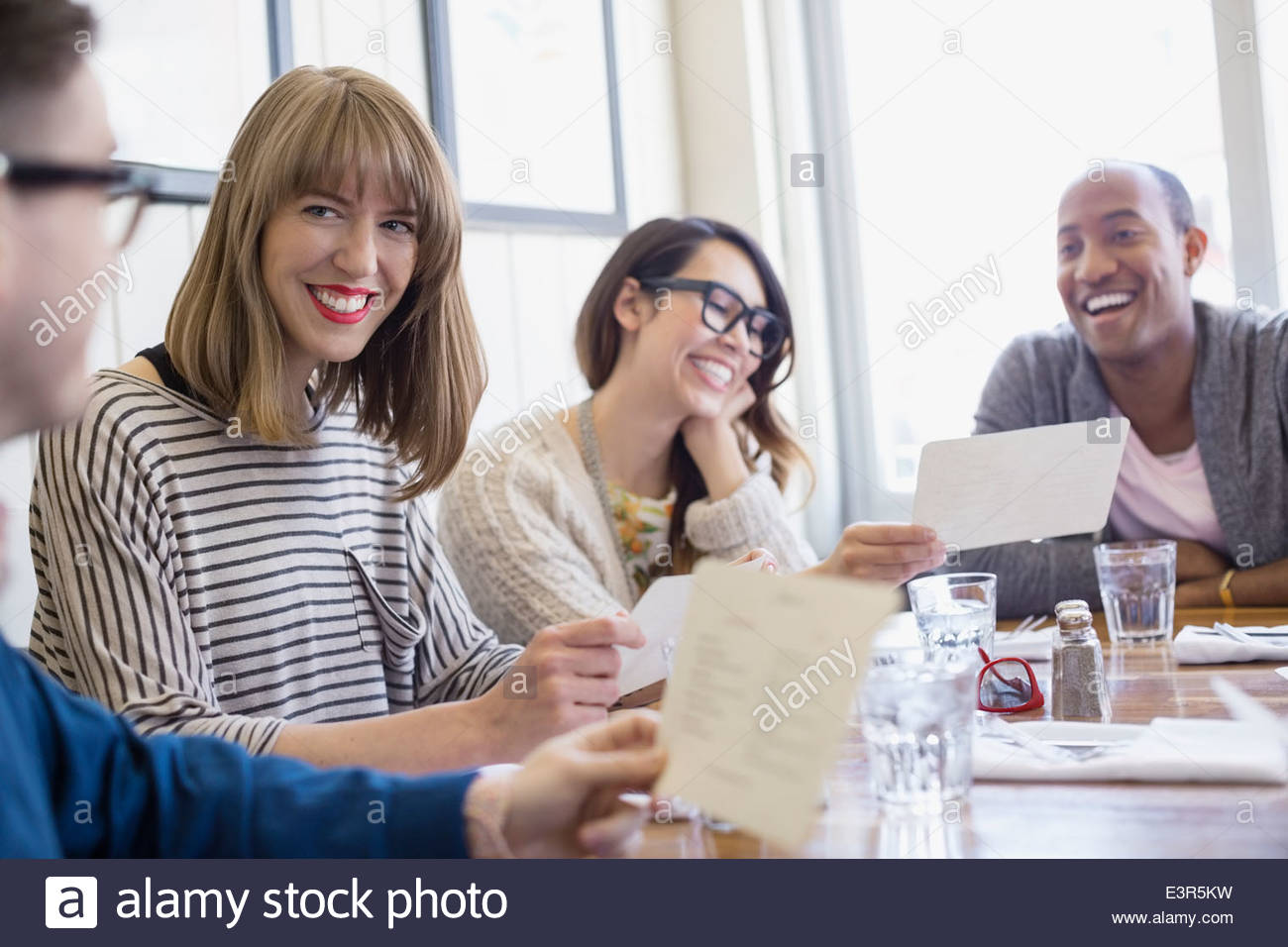 Friends looking at menus at bistro table Stock Photo - Alamy