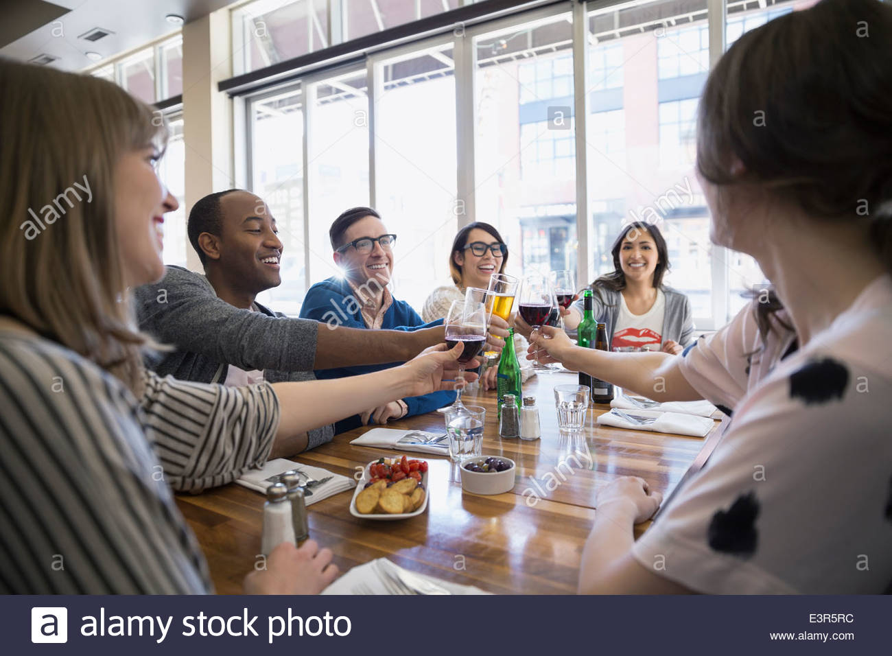 Friends toasting glasses at bistro table Stock Photo - Alamy