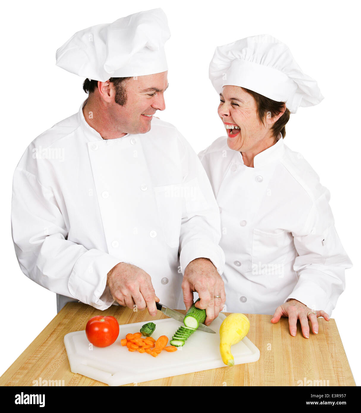 Two chefs working together in the kitchen and laughing as they cut up ...