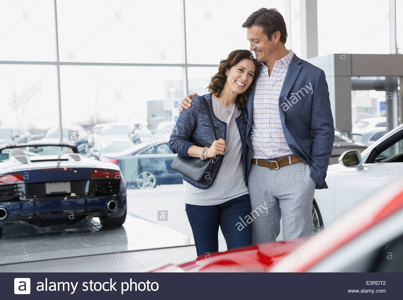 Couple hugging in car dealership showroom Stock Photo - Alamy