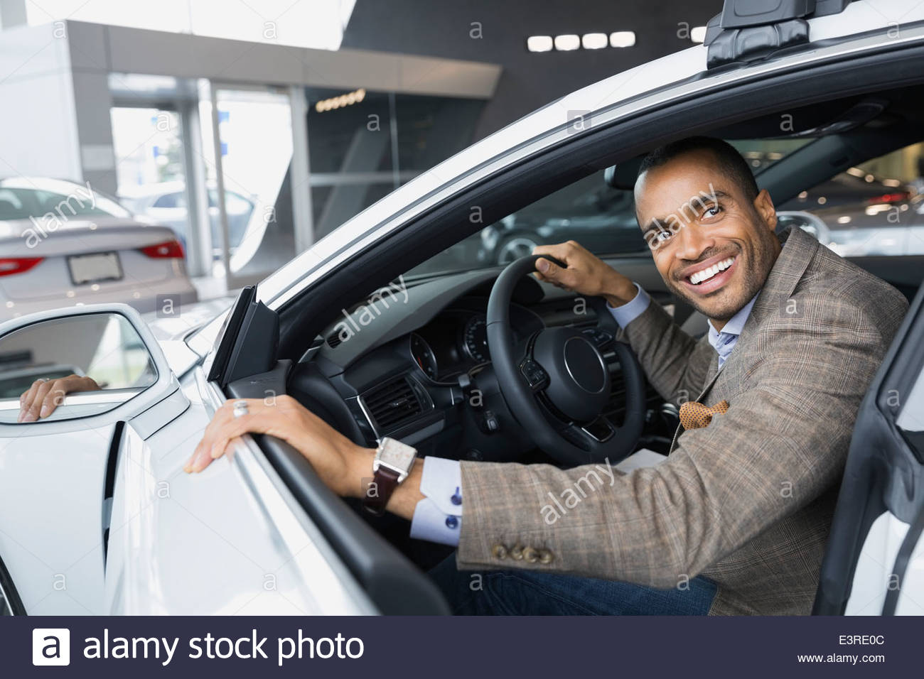 Smiling man inside car in car dealership showroom Stock Photo - Alamy