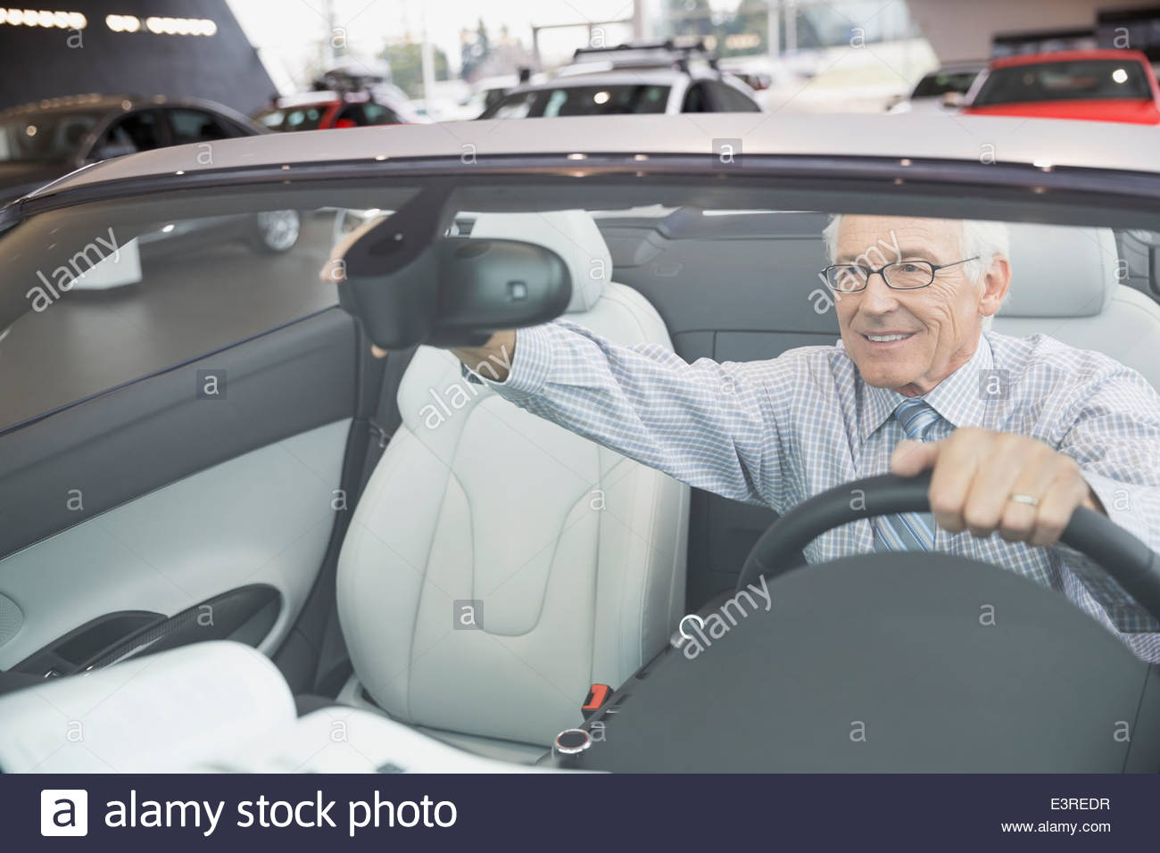Man adjusting rear-view mirror in showroom convertible Stock Photo - Alamy