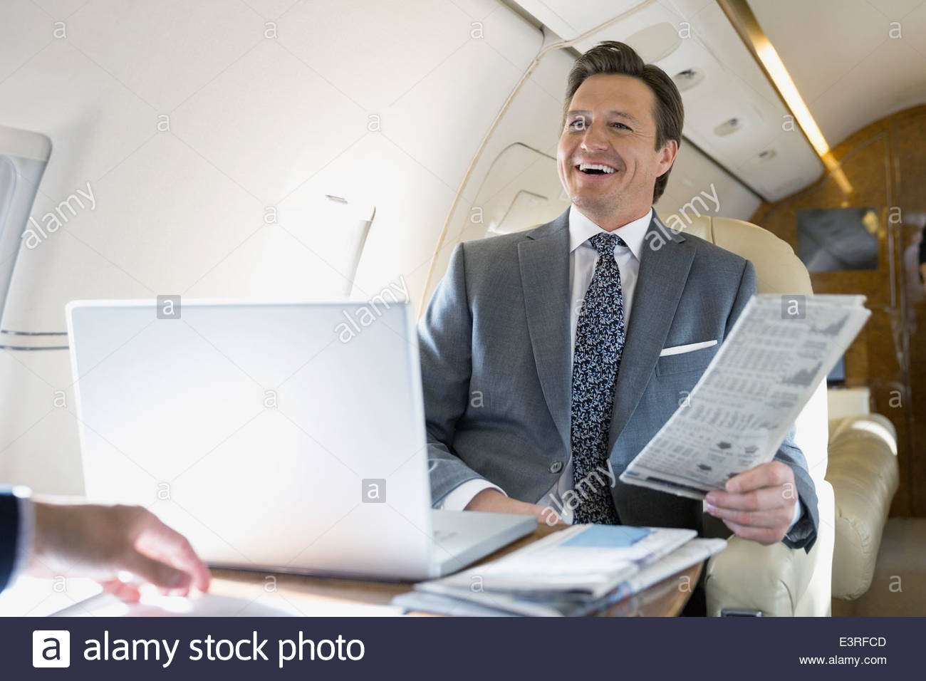 Businessman with newspaper laughing on corporate jet Stock Photo - Alamy