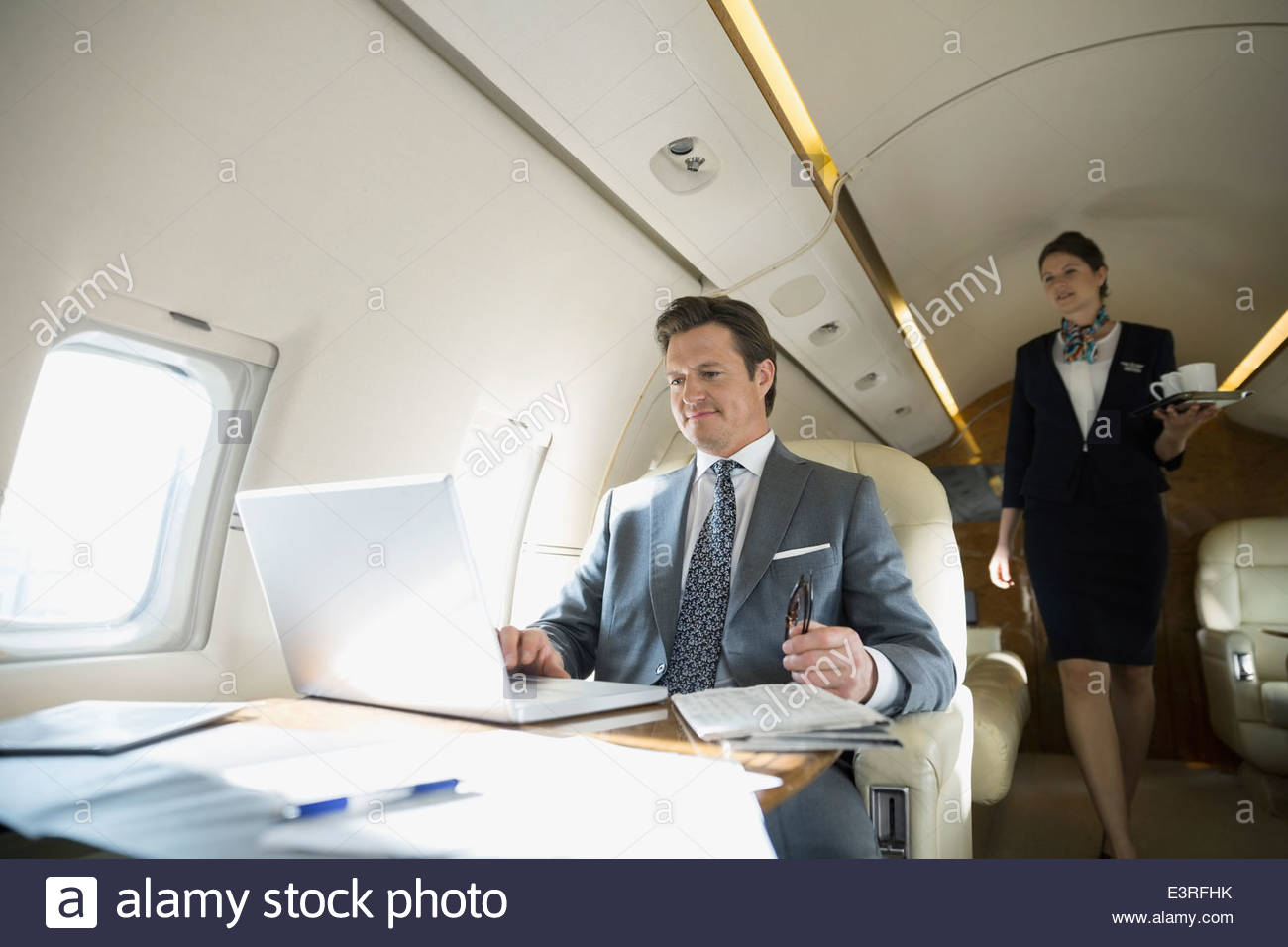 Flight attendant approaching businessman on corporate jet Stock Photo ...