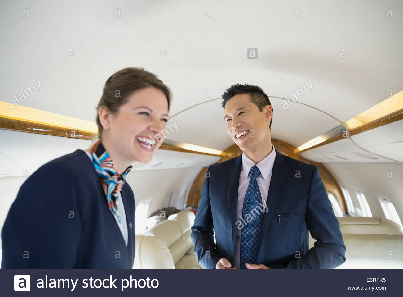 Businessman and flight attendant laughing on corporate jet Stock Photo ...