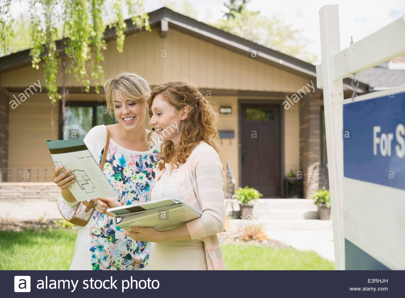 Realtor showing woman paperwork outside house Stock Photo - Alamy