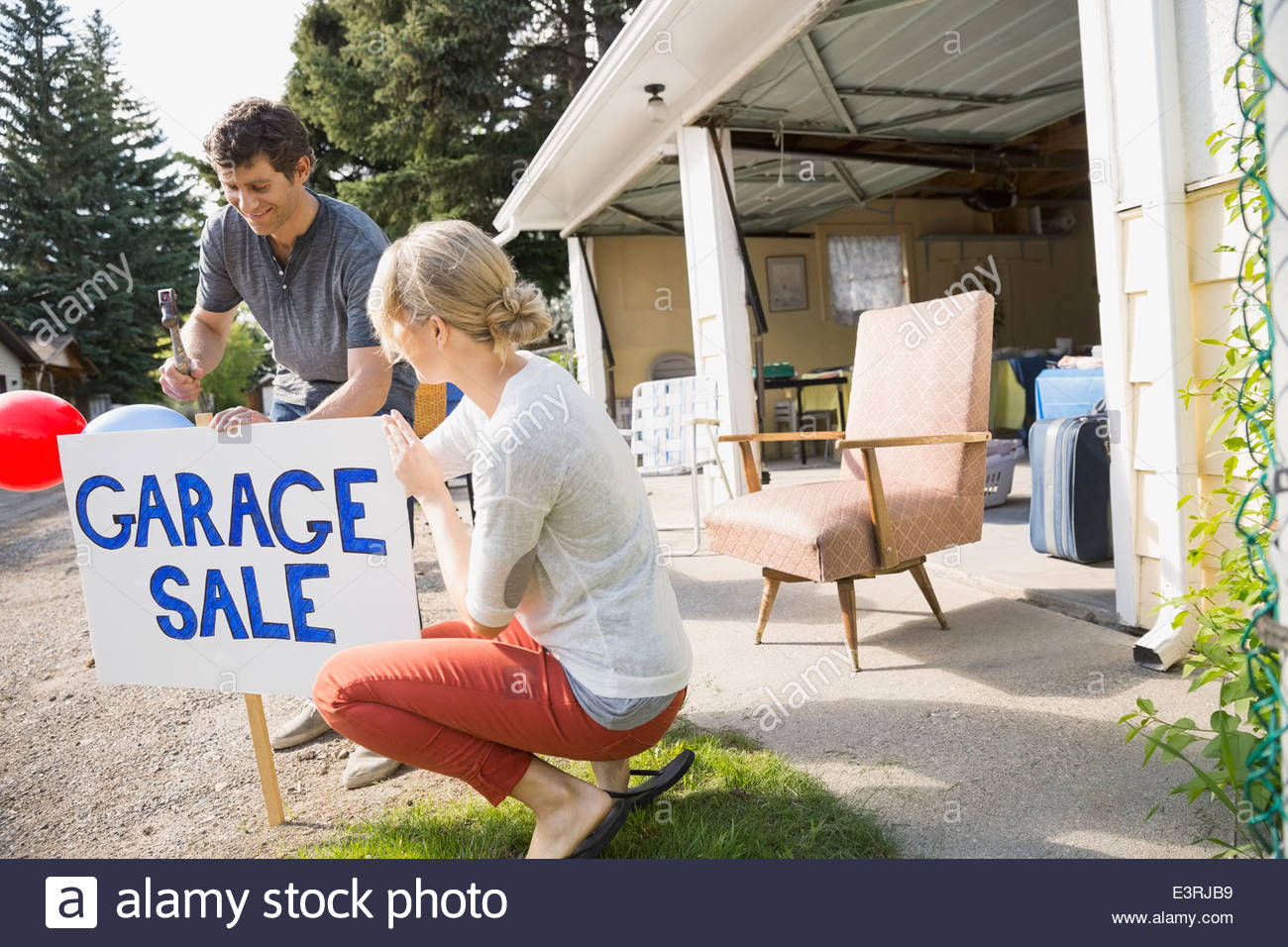 Couple putting up garage sale sign in yard Stock Photo - Alamy