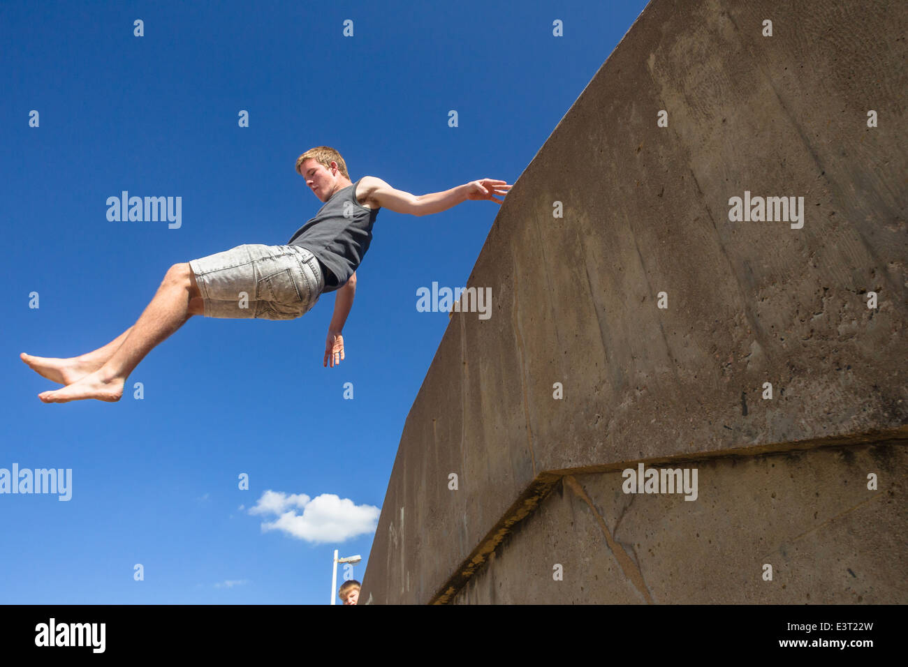 Teen boy jumping somersaults sequence against blue sky in park-our ...
