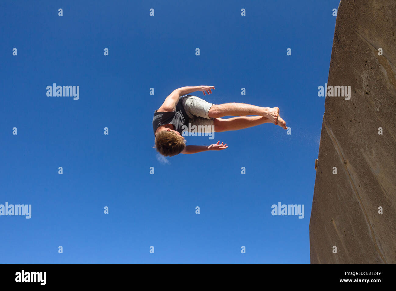 Teen boy jumping somersaults sequence against blue sky in park-our ...