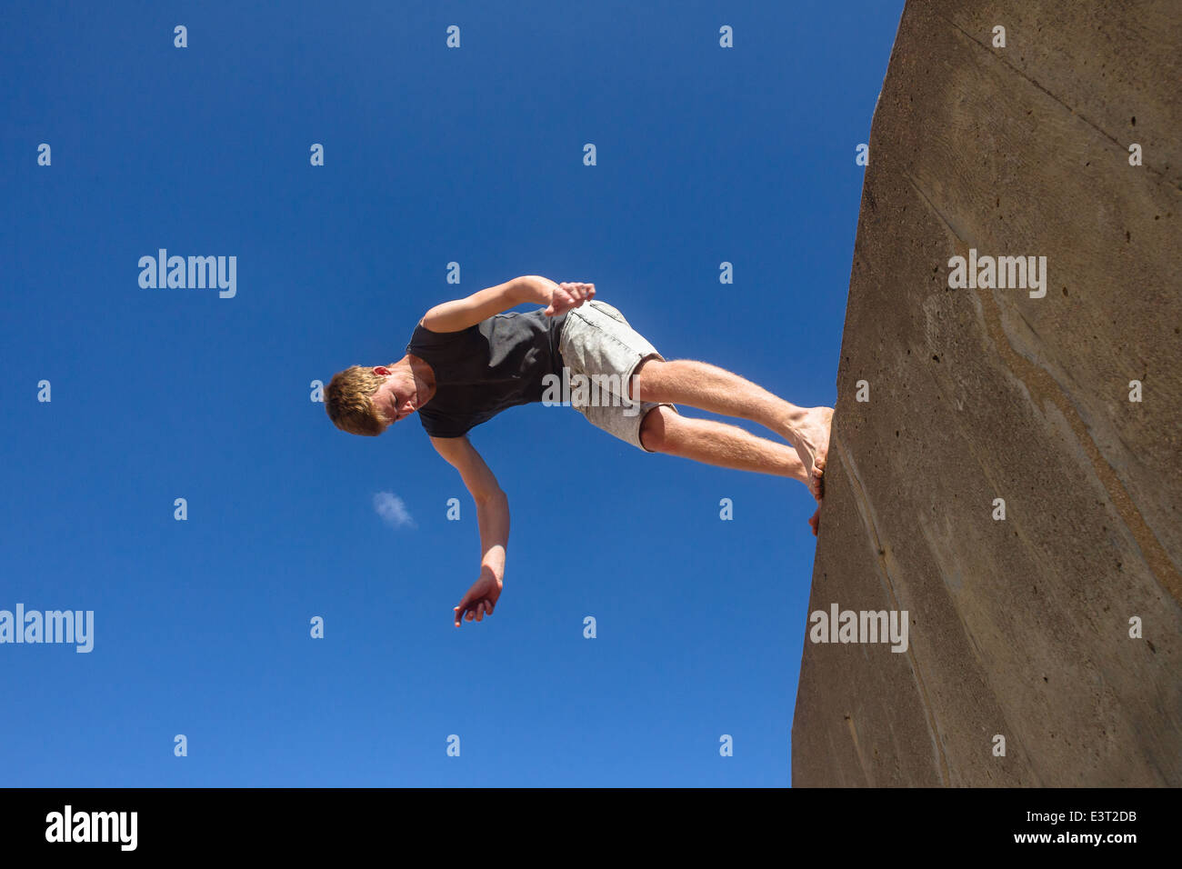 Teen boy jumping somersaults sequence against blue sky in park-our ...