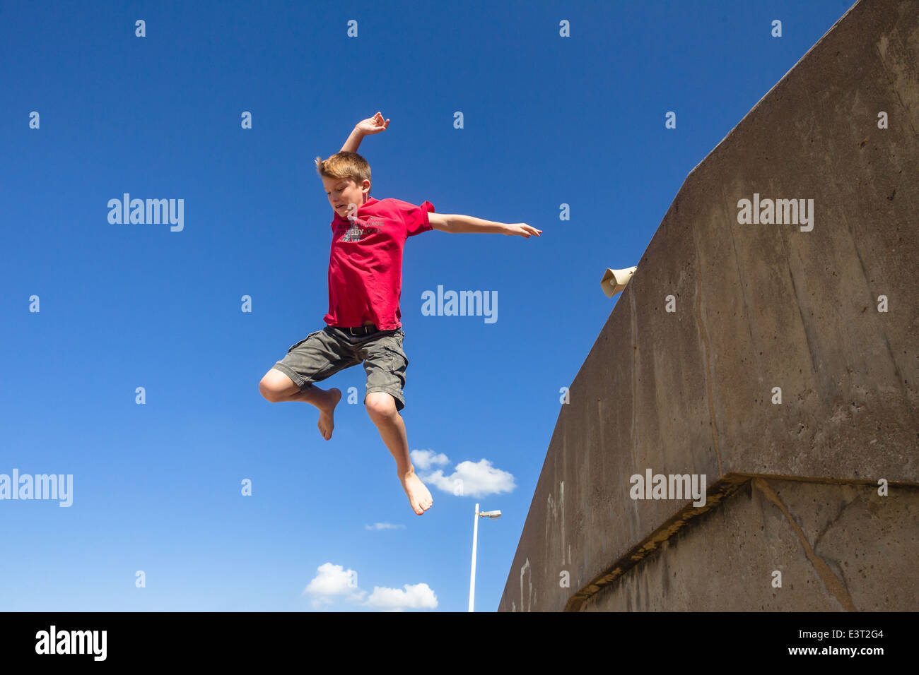 Teen boy jumping over concrete wall in thrill challenge excitement ...