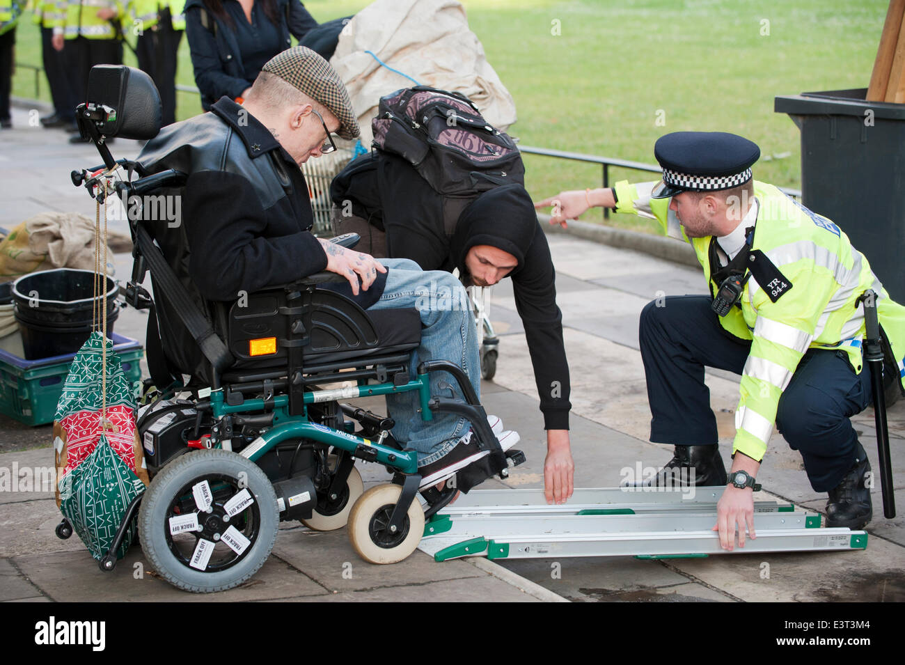 London, UK. 28th June, 2014. Police officer helsp man in wheelchair at ...