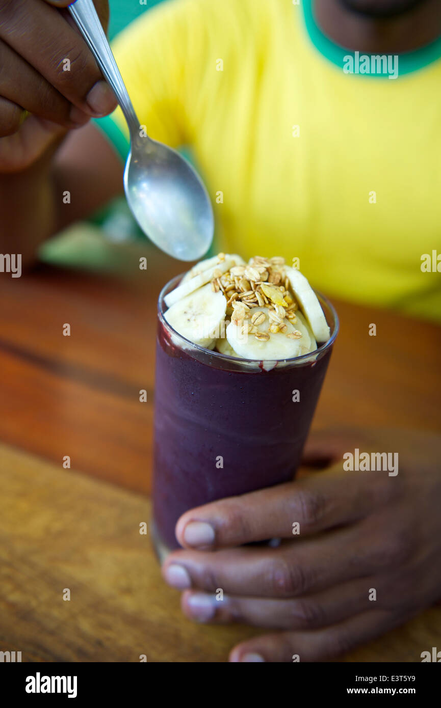 Brazilian man in Brazil colors shirt eating a cup of fresh frozen acai ...