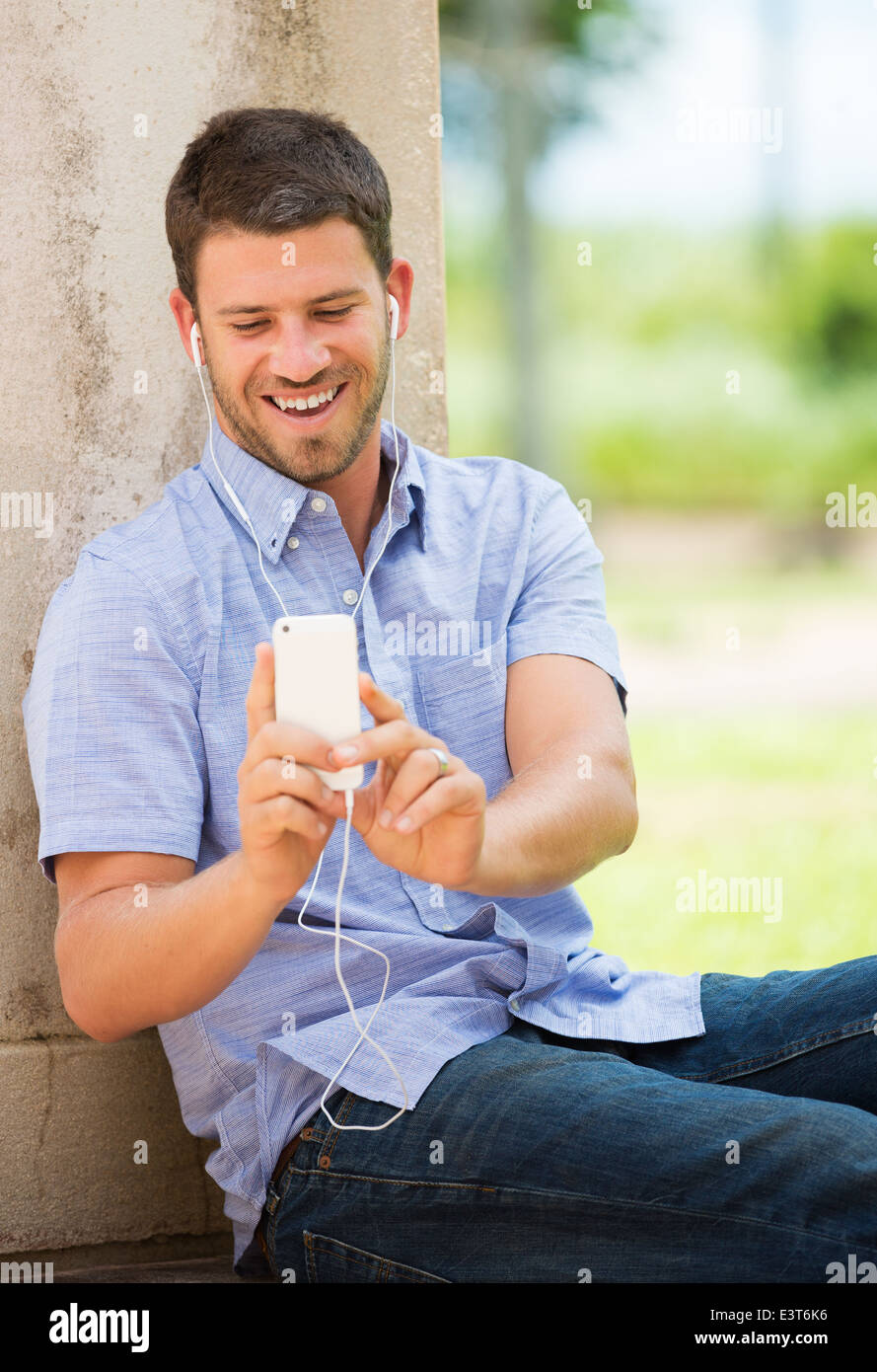 Young man using cell phone and head phones outside Stock Photo - Alamy