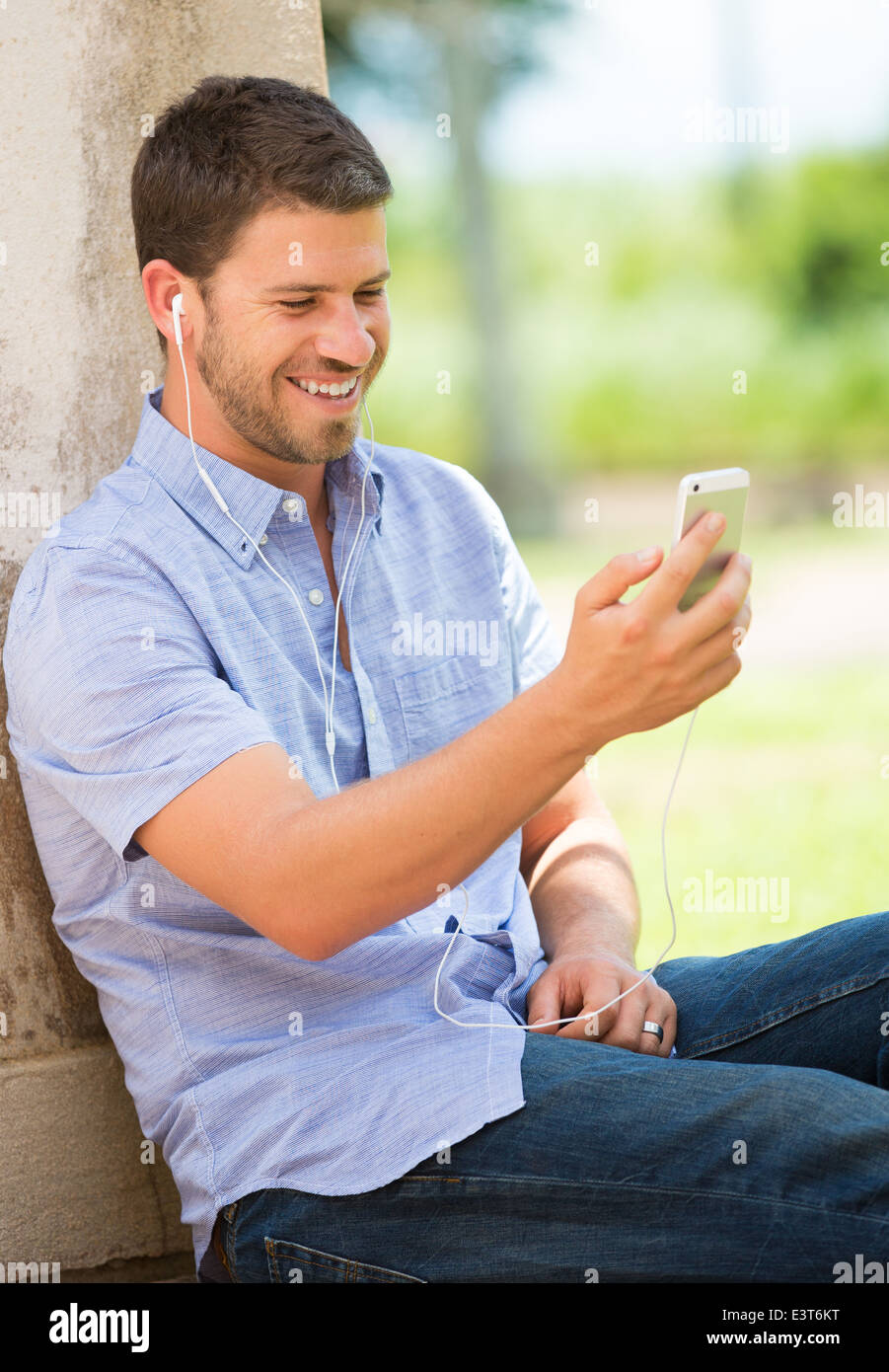 Young man using cell phone and head phones outside Stock Photo - Alamy