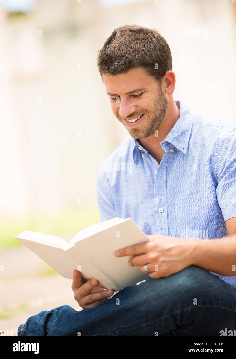 Young man reading book outside on steps Stock Photo - Alamy