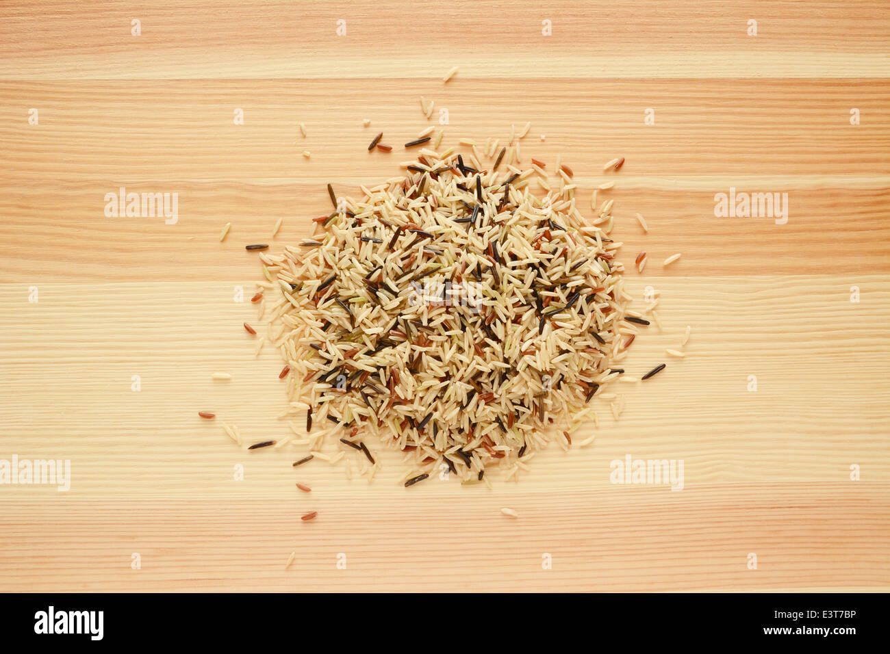 Wild rice, brown basmati and red camargue grains on a wood background ...
