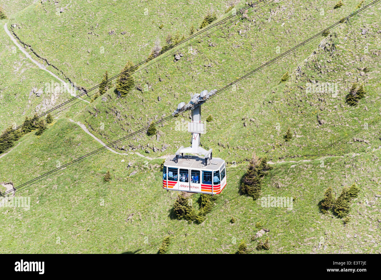 Red and white cable car travelling on the cableway between Wengen and ...
