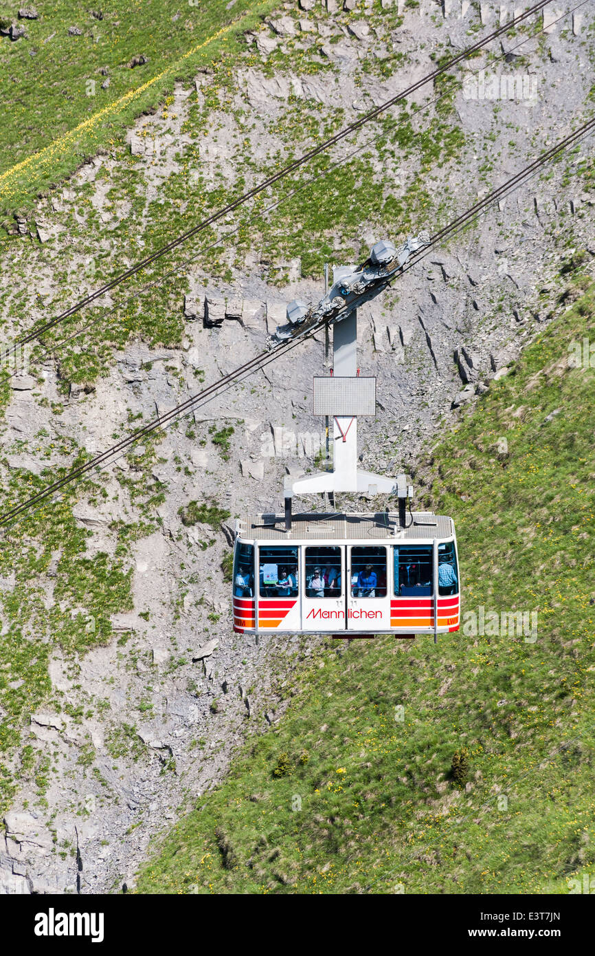 Red and white cable car travelling on the cableway between Wengen and ...