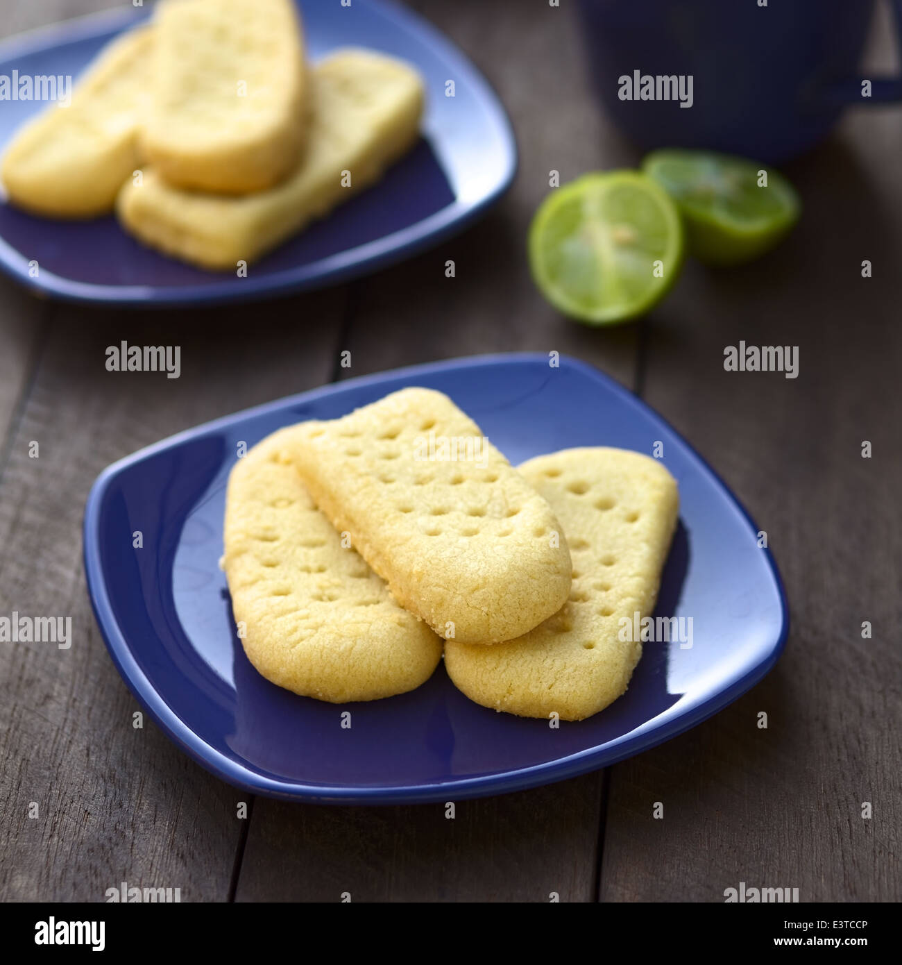 Homebaked shortbread biscuits on small plates with cup of tea in the ...