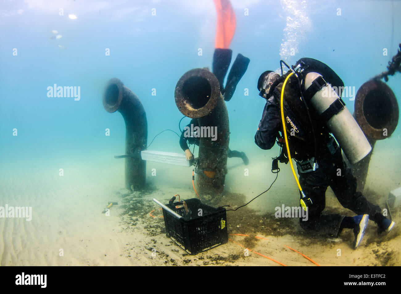 Commercial divers attach a zinc anode to a brine discharge pipe Stock ...