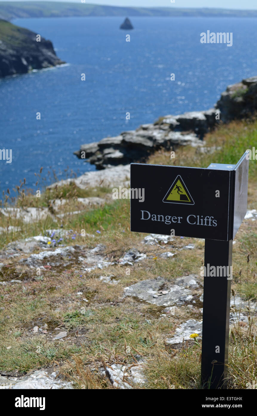 Danger cliff sign on the edge of steep cliffs on the Cornish coast at ...