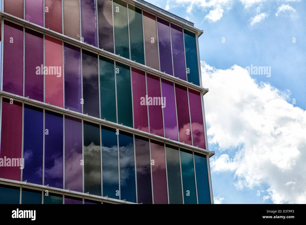 modern multi-colored glass building reflecting the blue sky and white ...