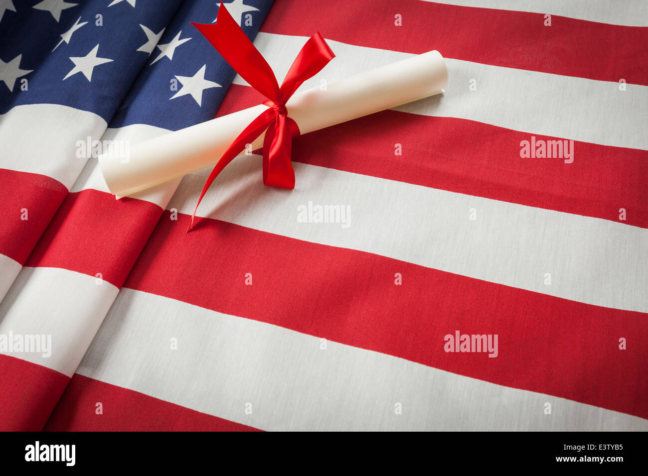 Red Ribbon Wrapped Diploma Resting on American Flag with Copy Space ...
