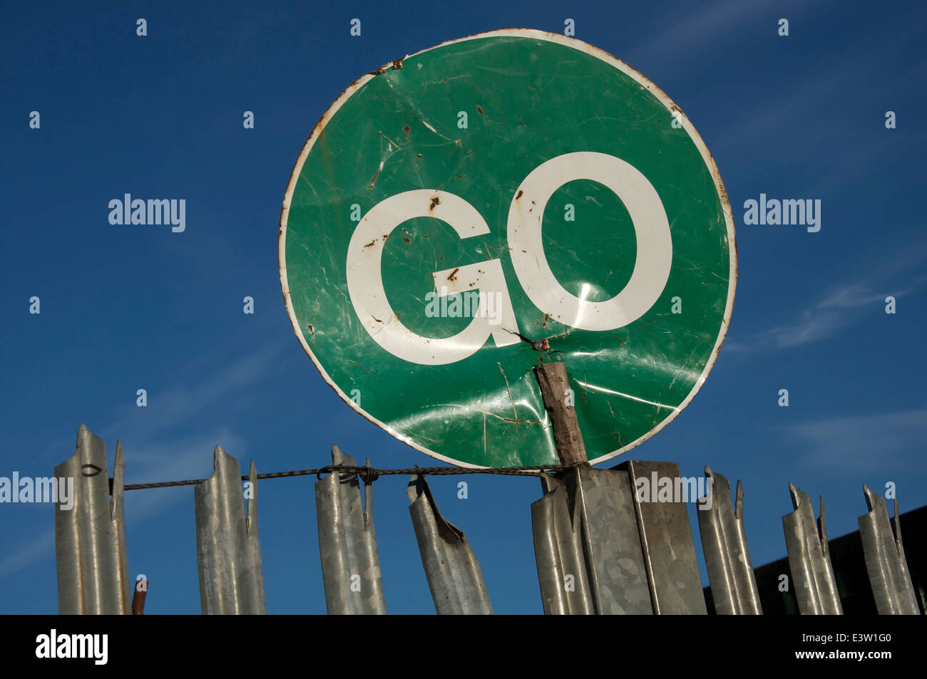 Metaphor. Positive concept. A circular GO sign, battered and worn, with ...