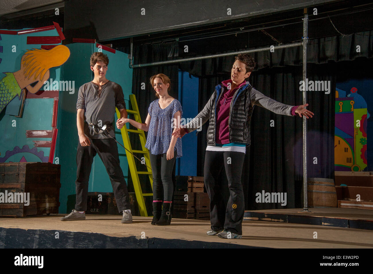 A high school drama teacher directs student cast members during ...