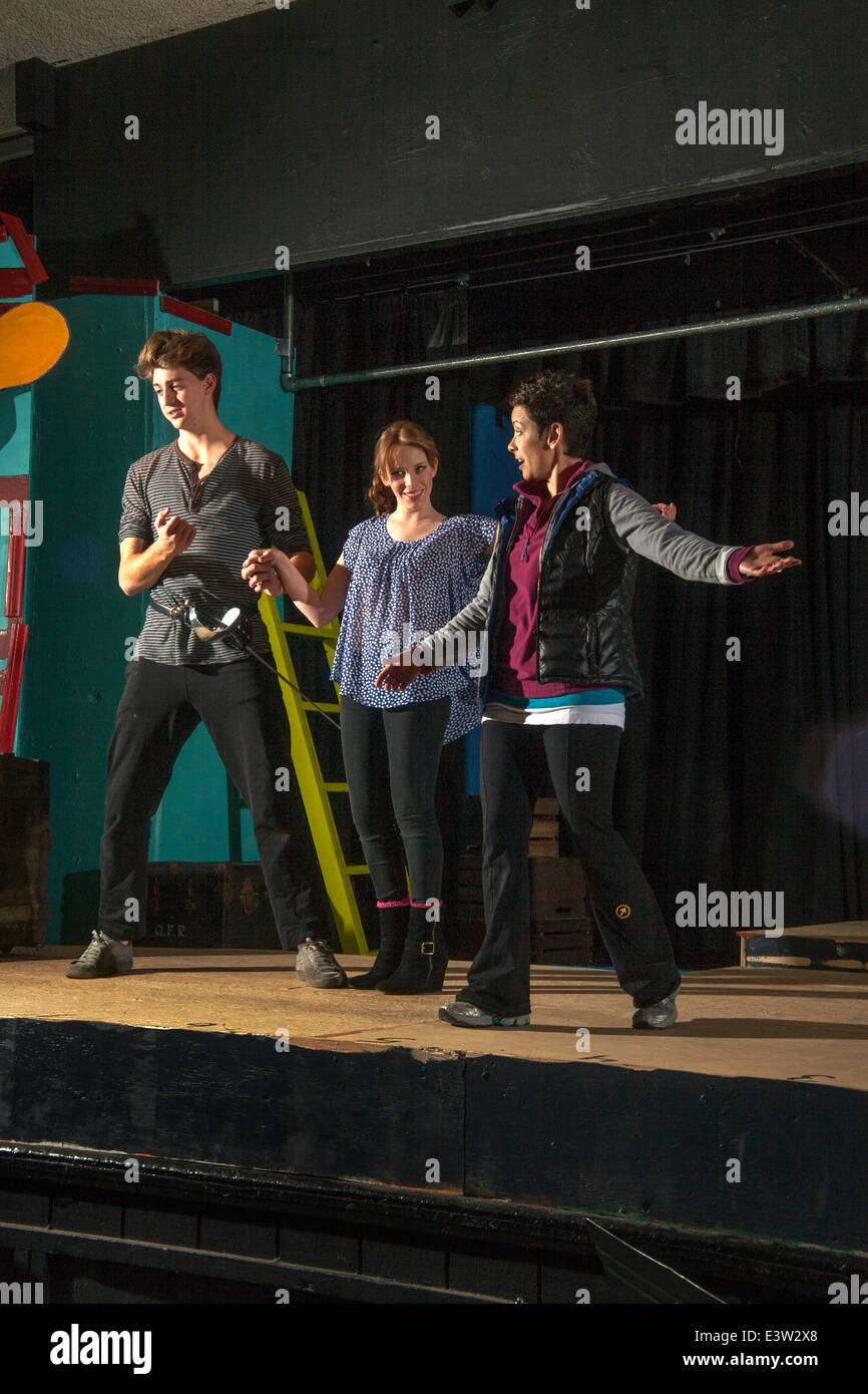 A high school drama teacher directs student cast members during ...