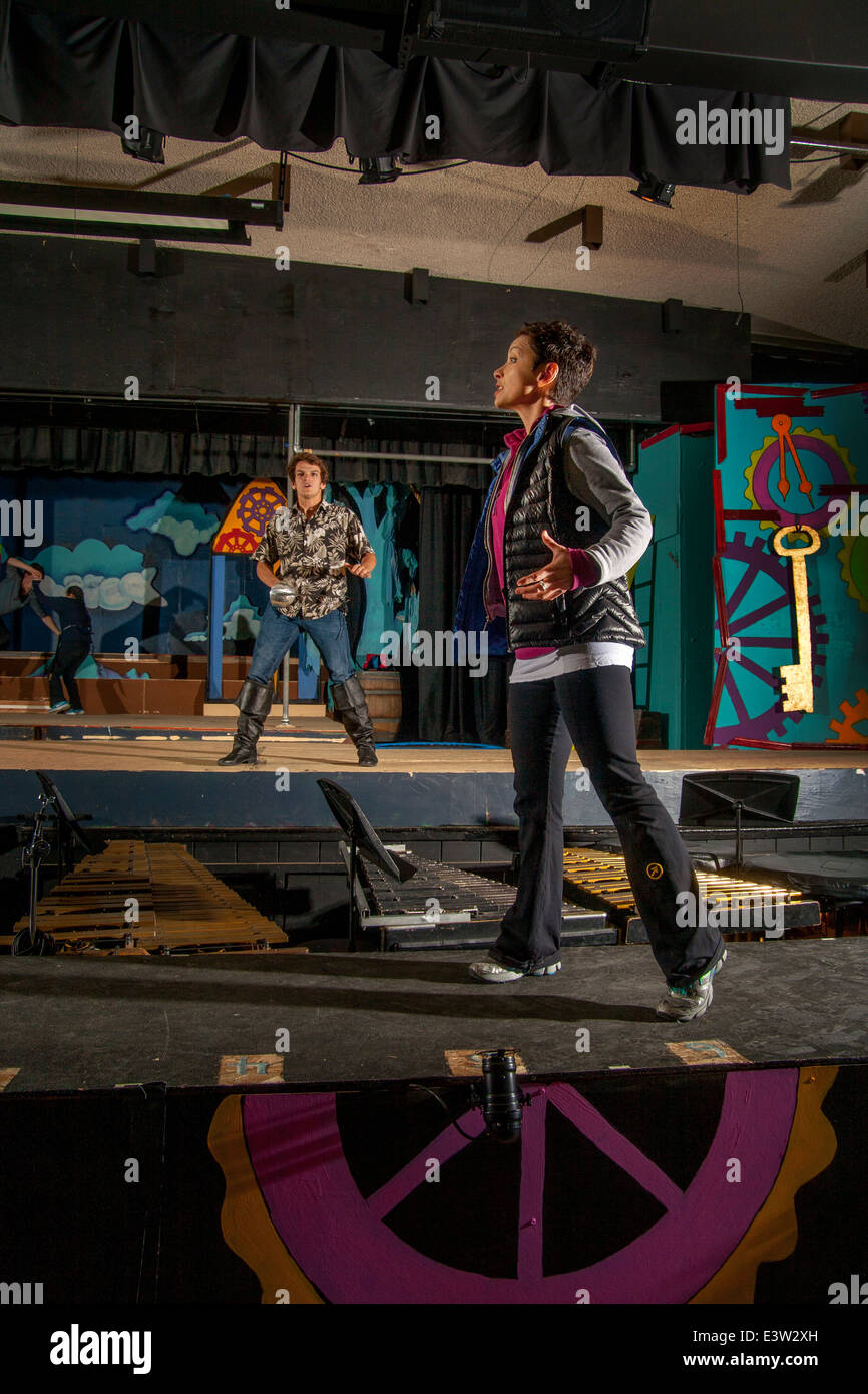 A high school drama teacher directs a student cast member during ...