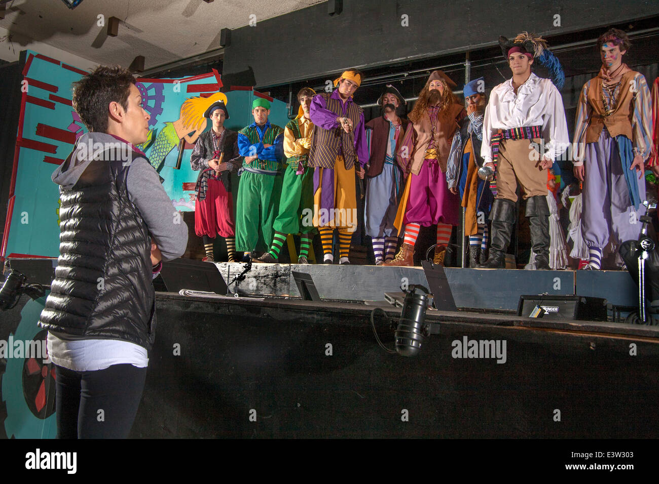 A high school drama teacher directs costumed student cast members ...