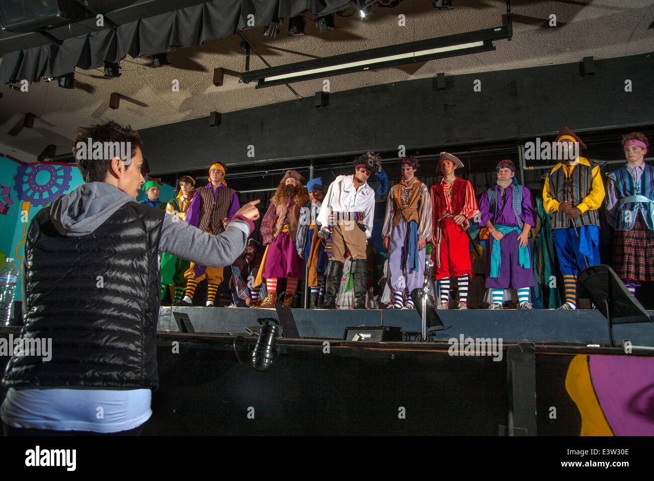 A high school drama teacher directs costumed student cast members ...