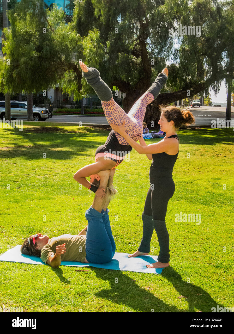 A trio of athletes perform Acroyoga in Balboa Park, San Diego, CA. Note ...