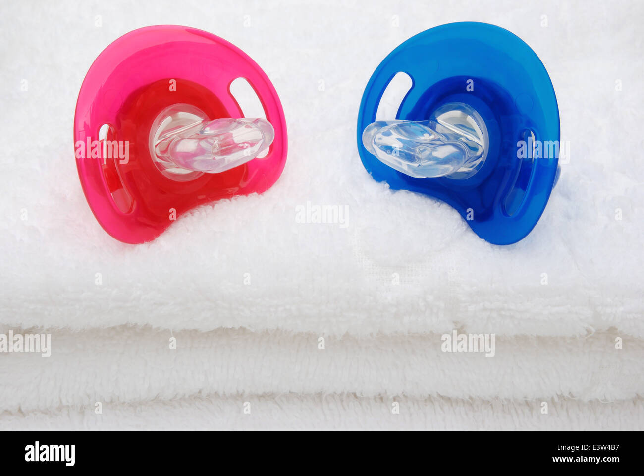 red and blue pacifiers on white towel Stock Photo - Alamy