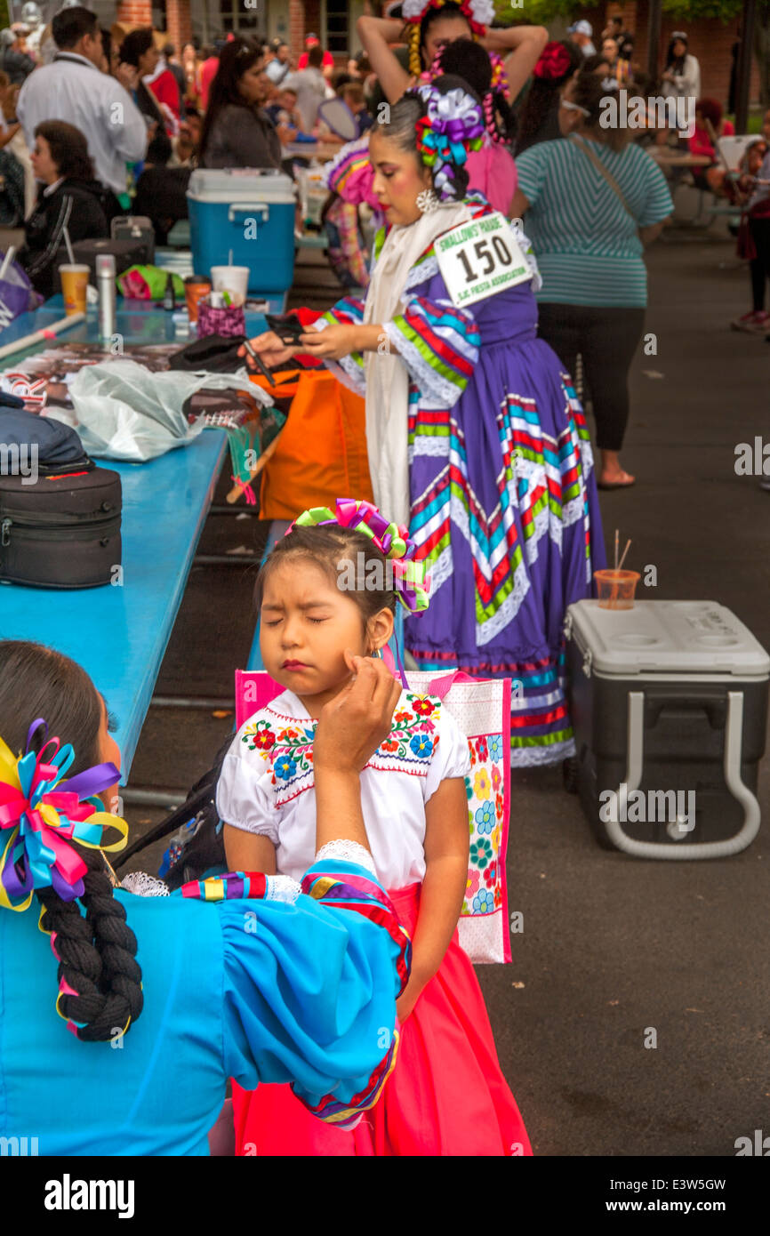 A Hispanic girl in ethnic Mexican costume gets made up by her mom ...