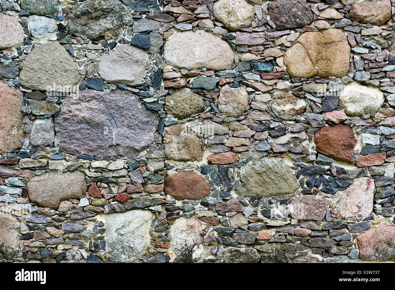 Wall made of rough granite small and large stones. Natural background ...