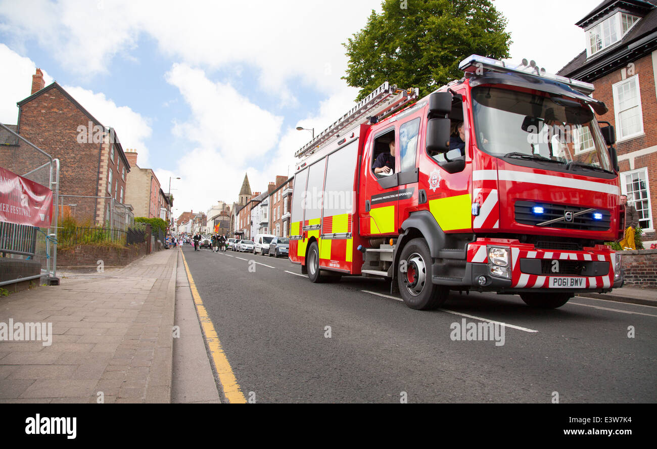 A Volvo Fire engine leads a town carnival procession with its blue ...