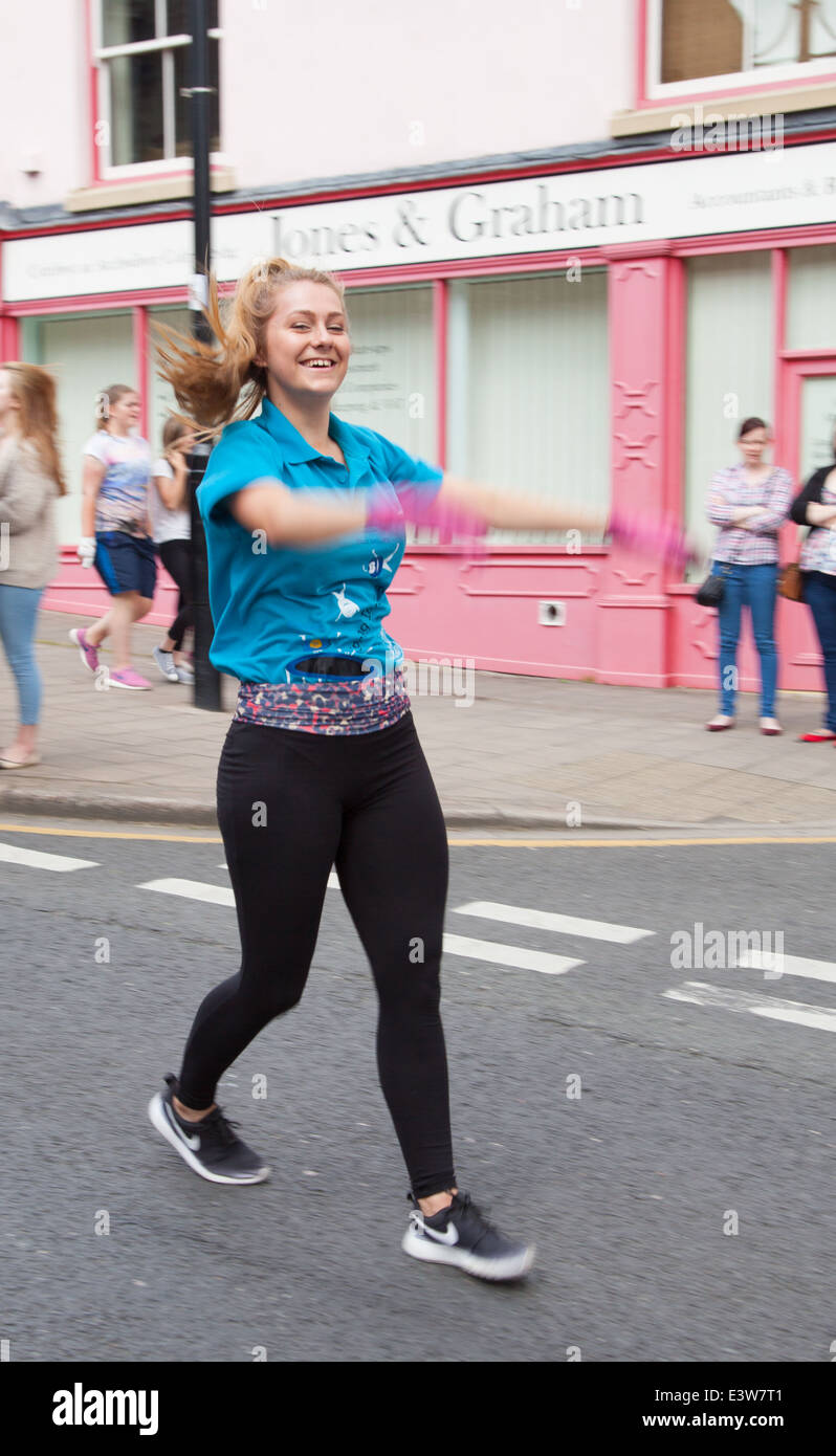 A happy young woman dancing / walking down a road as part of a parade ...
