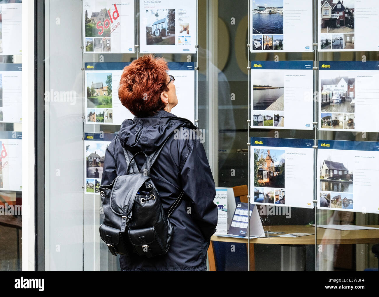 A woman looking in an estate agents window Stock Photo - Alamy