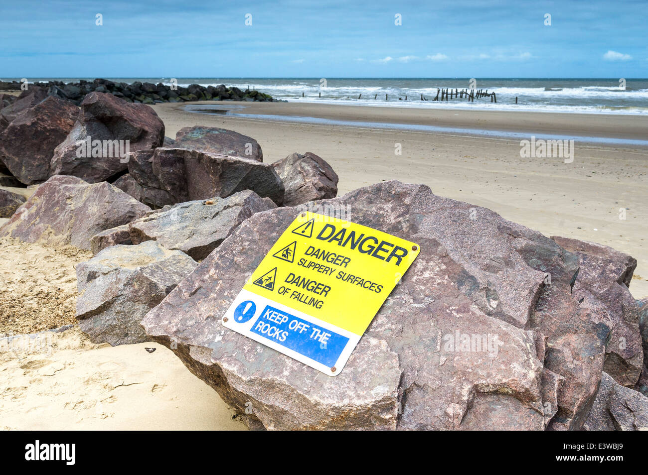 A warning sign on rocks that form the sea defences at Happisburgh Stock ...