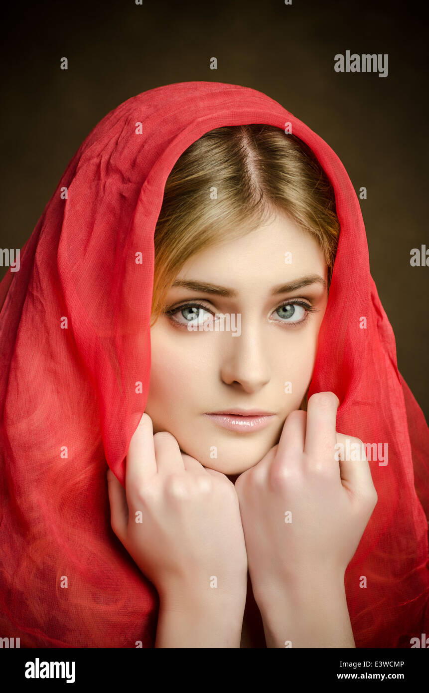 Sad young woman covered with a red scarf Stock Photo - Alamy