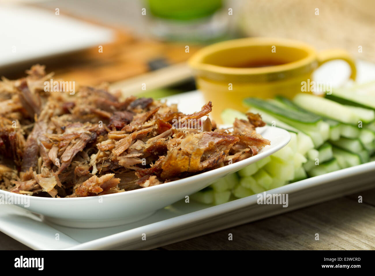 Crispy aromatic duck, shredded on a platter with cucumber and spring ...