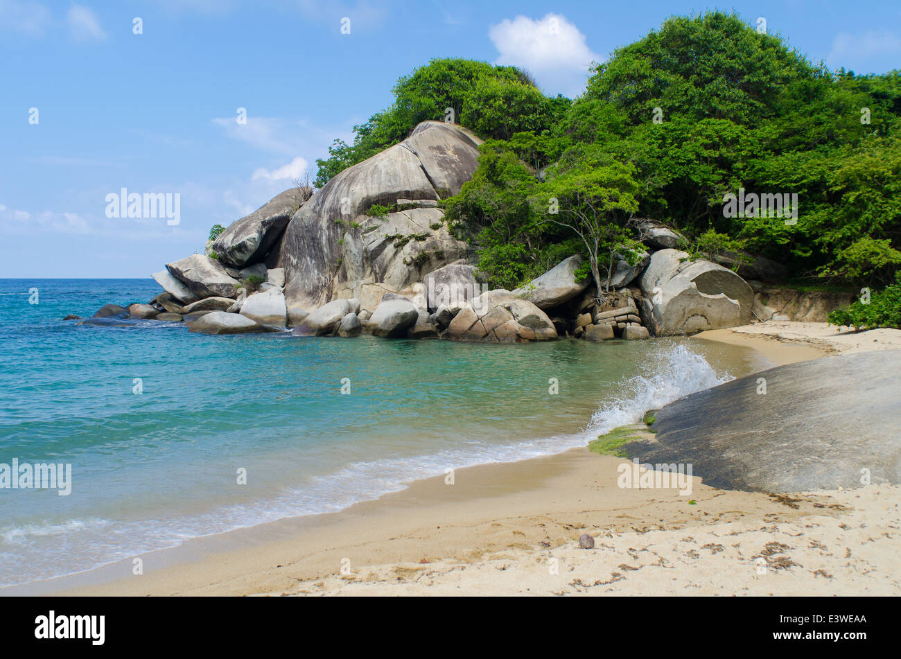 A sandy beach on the ocean with rock formations and forest Stock Photo ...