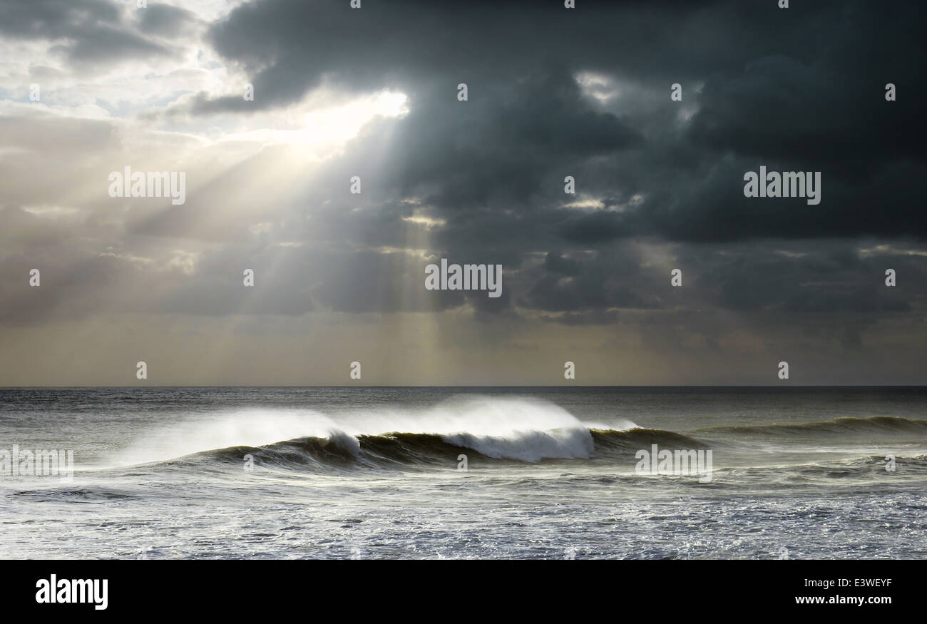 Beautiful seascape with bright sun rays and dark clouds over a wavy sea ...