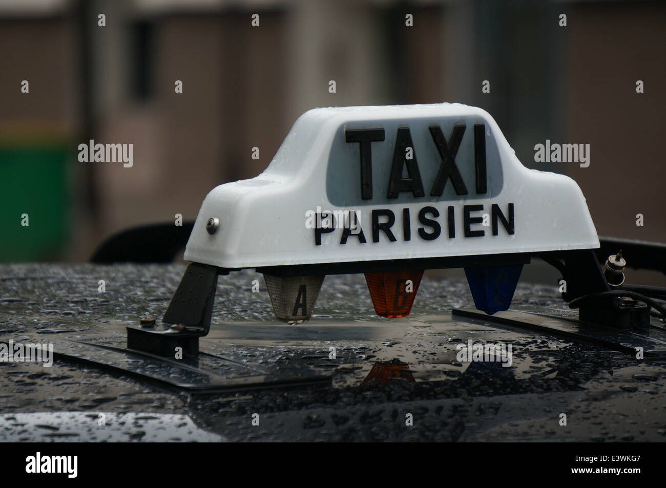 A black Paris taxi with a white Taxi Parisien sign in the rain wait ...