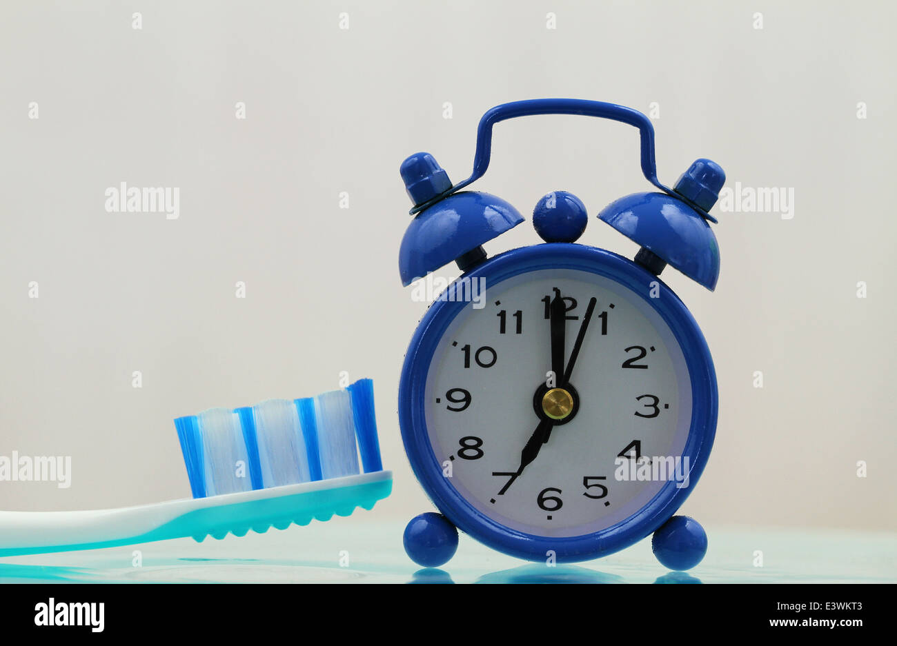Miniature clock showing 7 am with blue toothbrush Stock Photo - Alamy