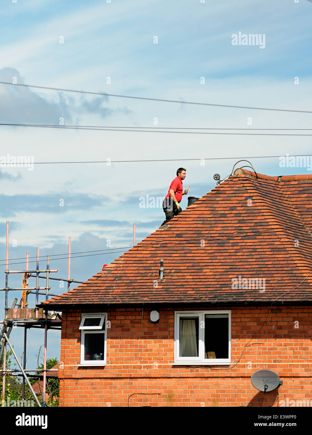 A man working at hight re-pointing a roof England uk Stock Photo - Alamy
